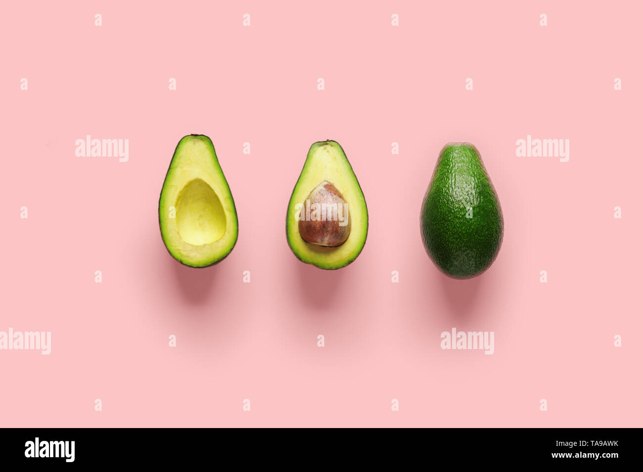 Whole avocado fruit and two halves in a row isolated on pink background ...