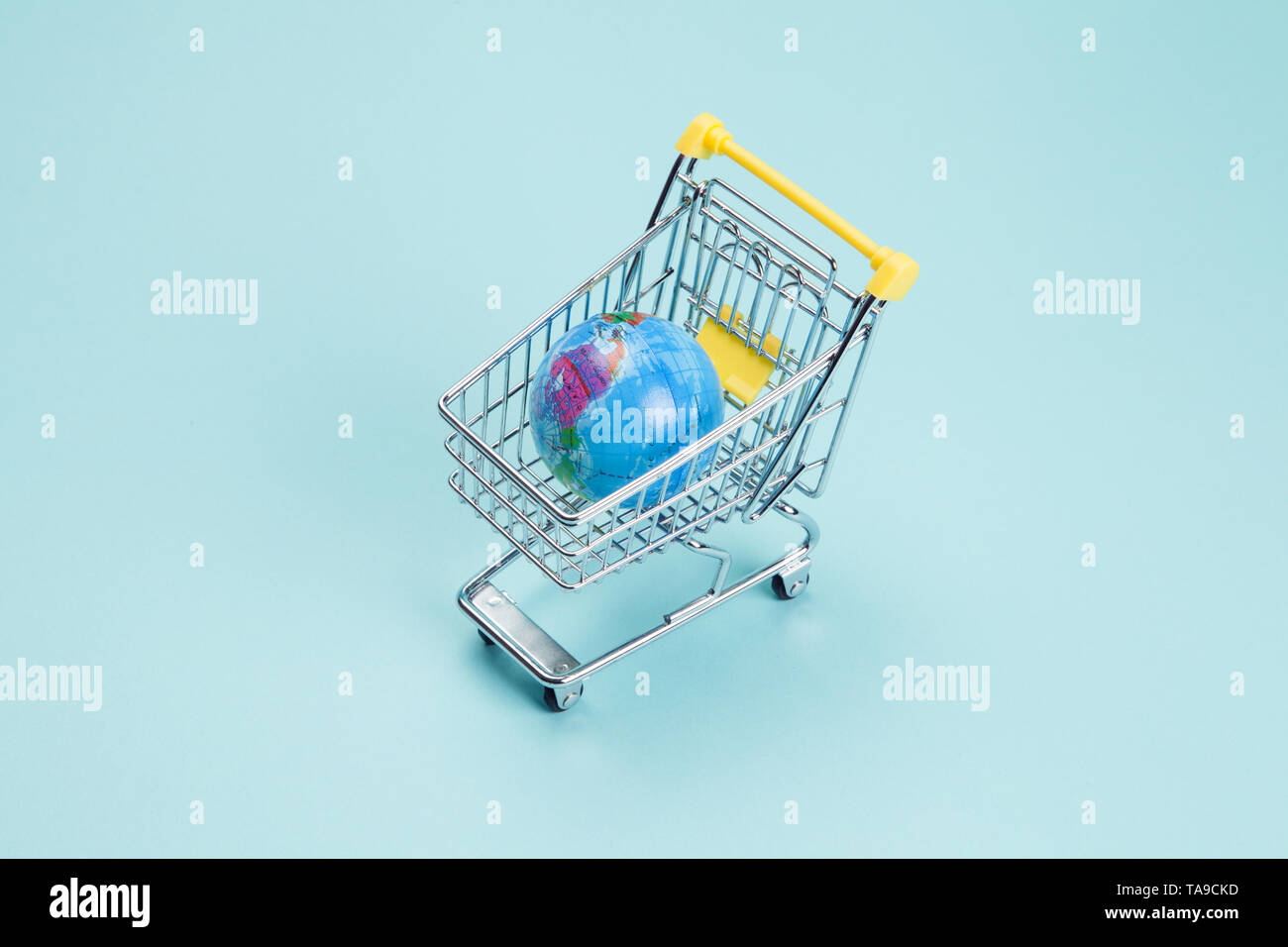 a planet earth in a supermarket shopping cart on a turquoise background ...