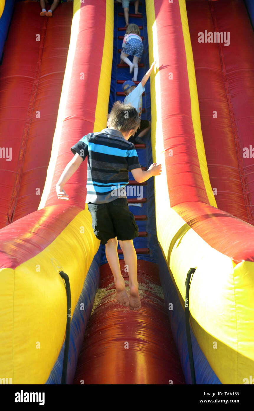 Young Boy Jumping with Delight as he Ascends a Bounce Castle Slide ...