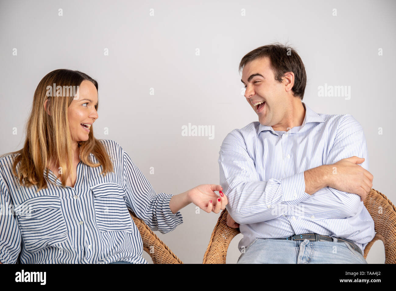 Young couple pose in a photo studio sitting in a chair and laughing a ...