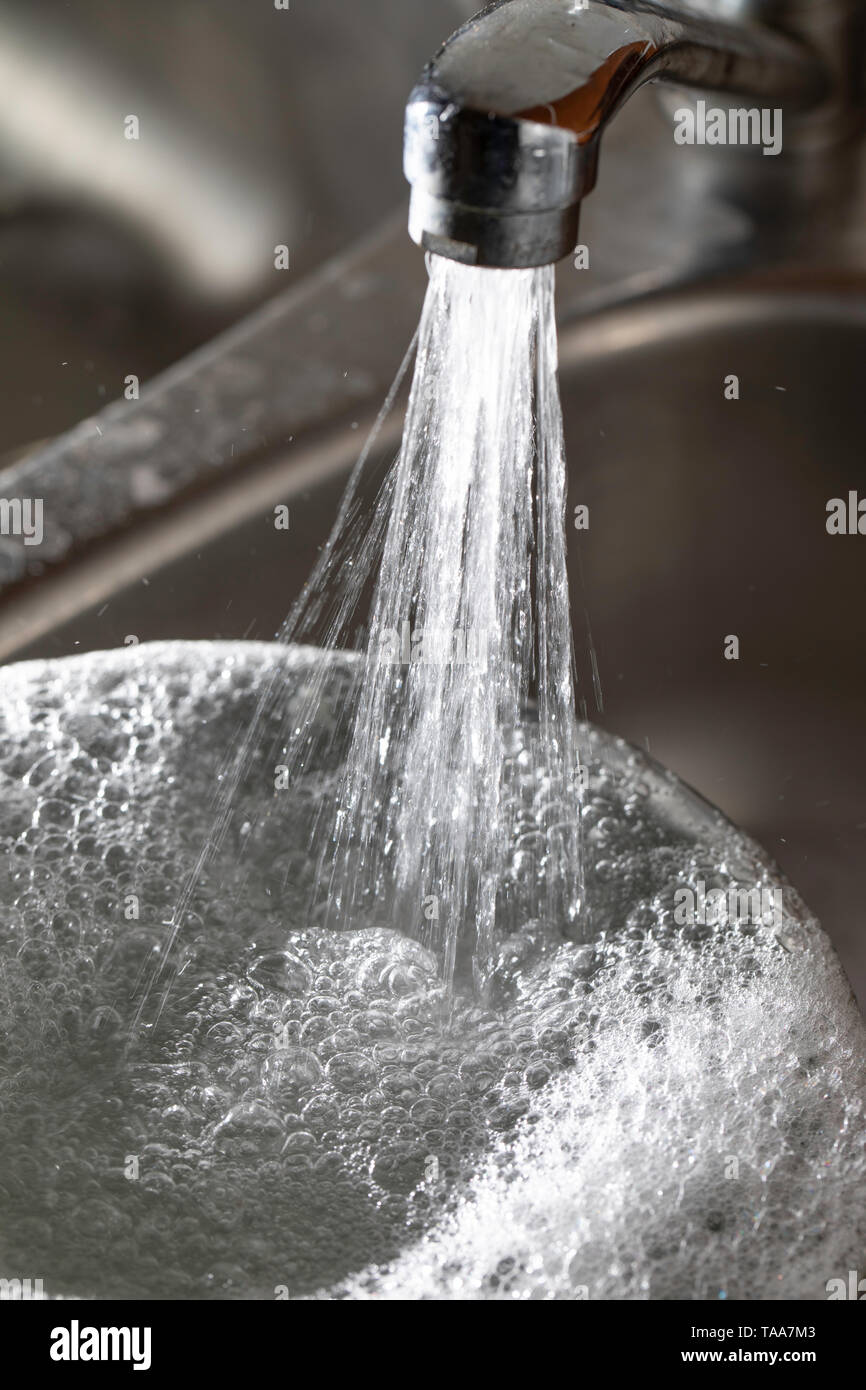 Washing dishes in running tap water - dirty sink, wastage of water ...