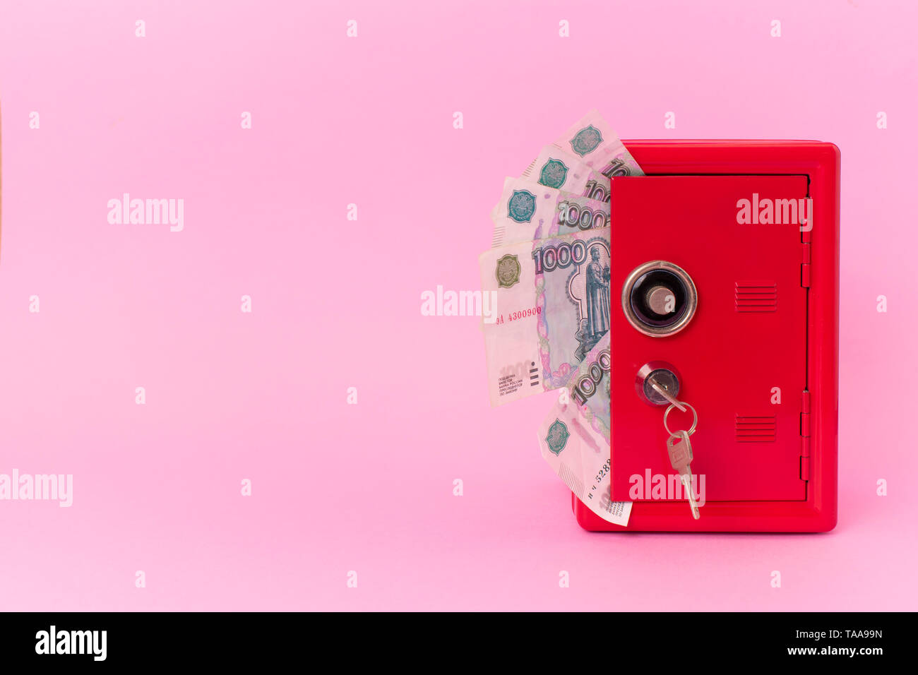 red safe on a fan of russian money on white background. bank with key ...