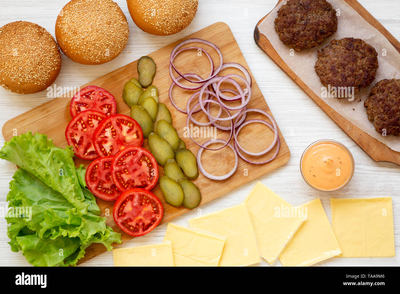 Cheeseburger ingredients on a white wooden background, top view. Flat ...