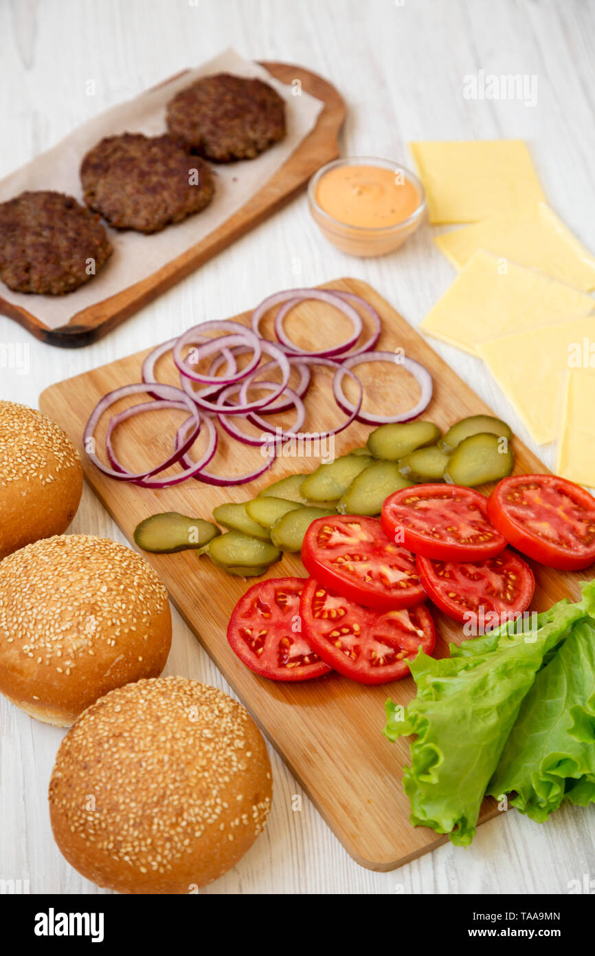 Cheese burger ingredients on a white wooden background, side view ...