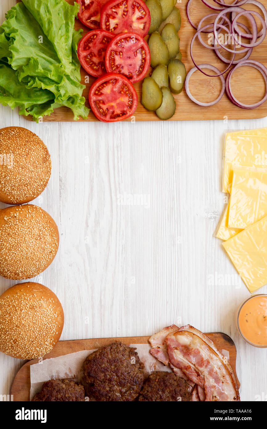 Cheese burger ingredients on a white wooden background, top view. From ...