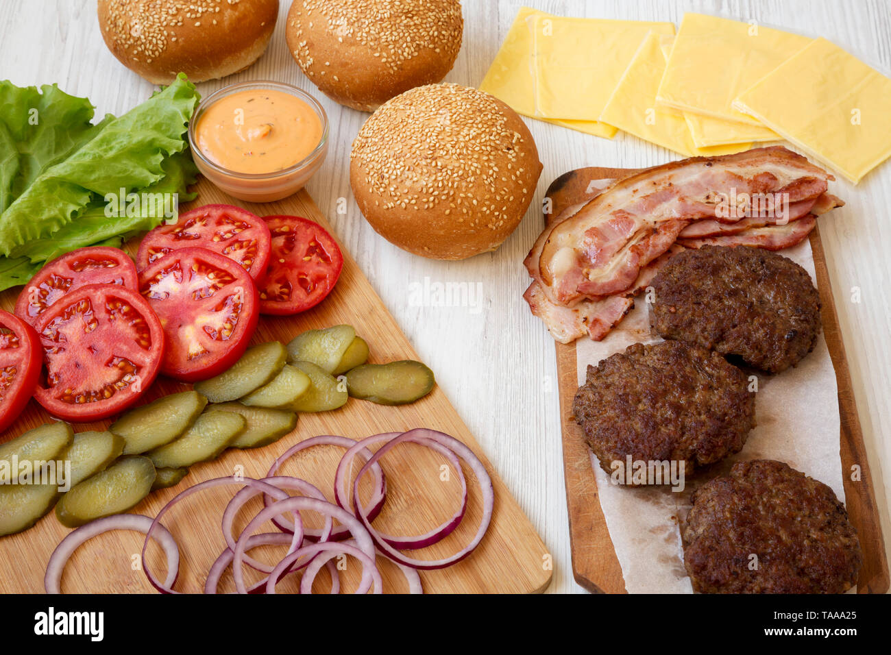 Cheeseburger ingredients on a white wooden background, side view. Close ...