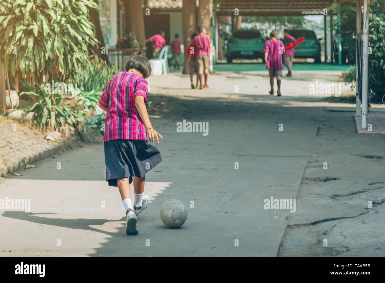 Back view of Girl student wear skirt to practice playing football alone ...