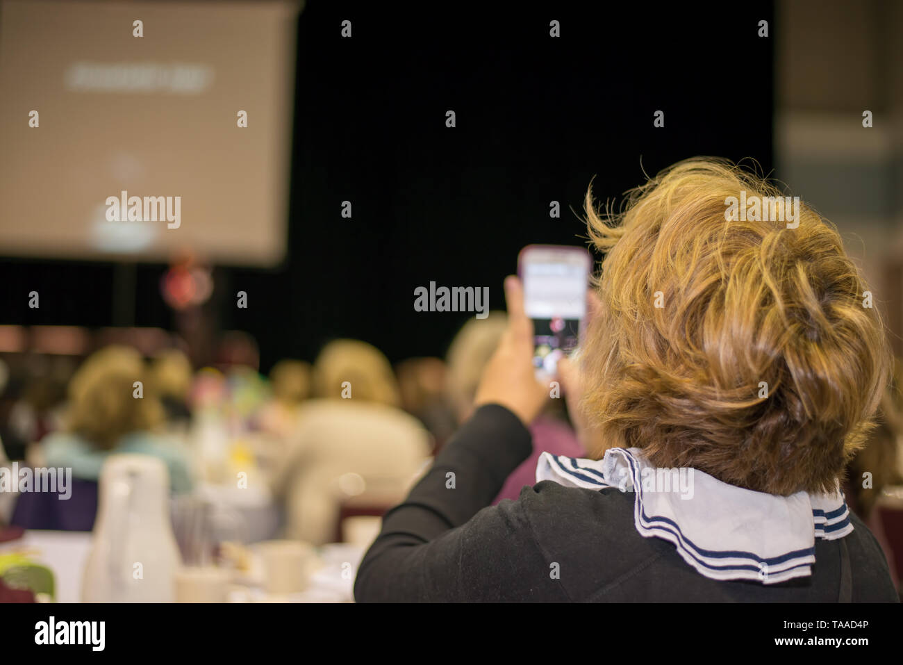 Woman using technology to help take in information while watching a ...