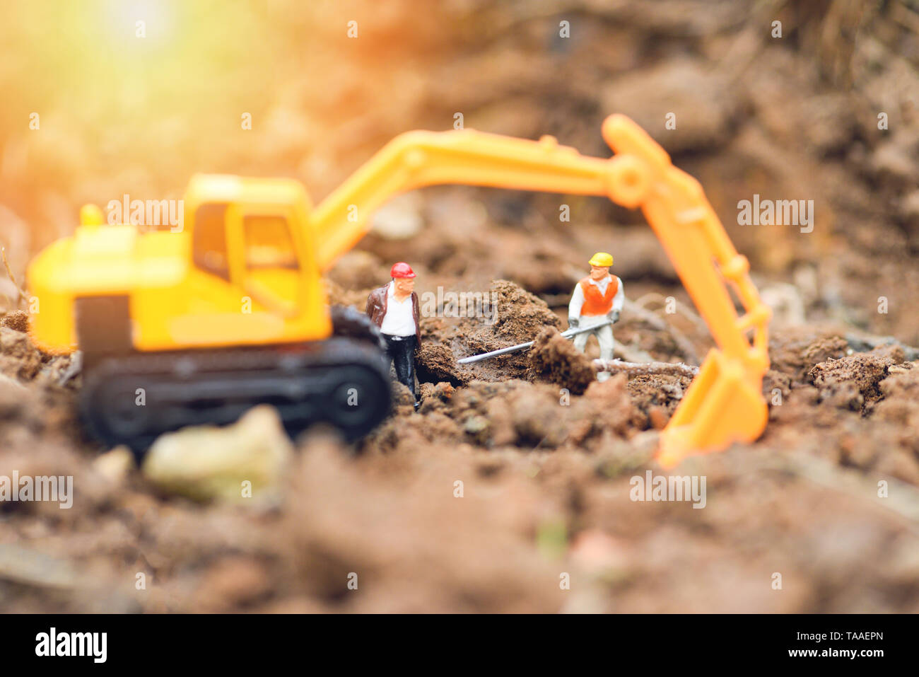 Construction worker figurines working digging ground soil with Backhoe ...