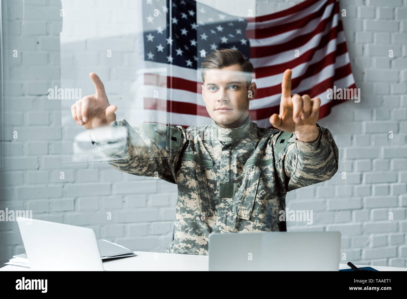 selective focus of handsome soldier in uniform pointing with fingers ...