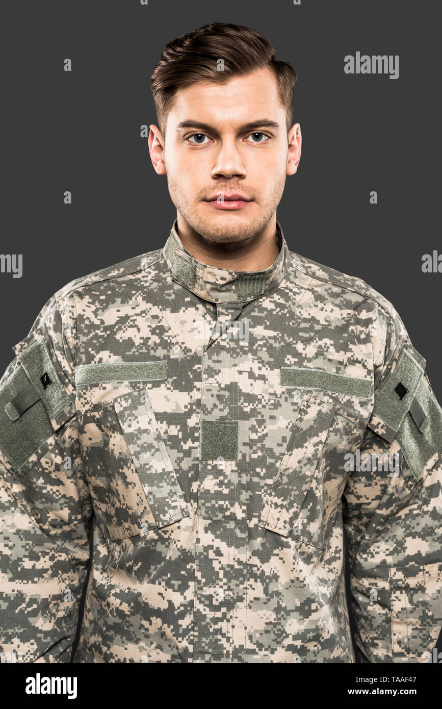 serious soldier in uniform looking at camera isolated on grey Stock ...
