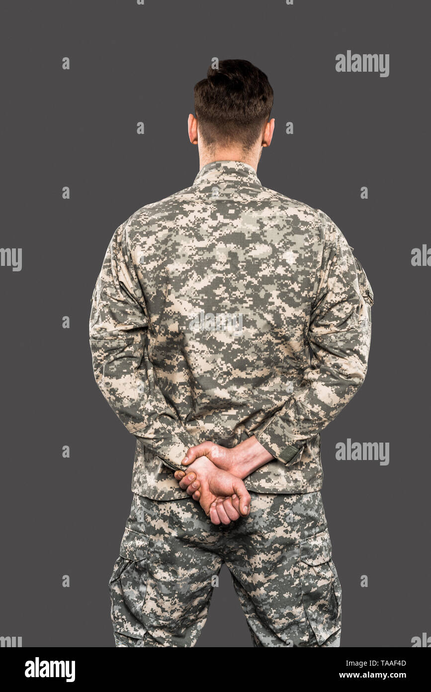 back view of soldier standing with clenched hands isolated on grey ...