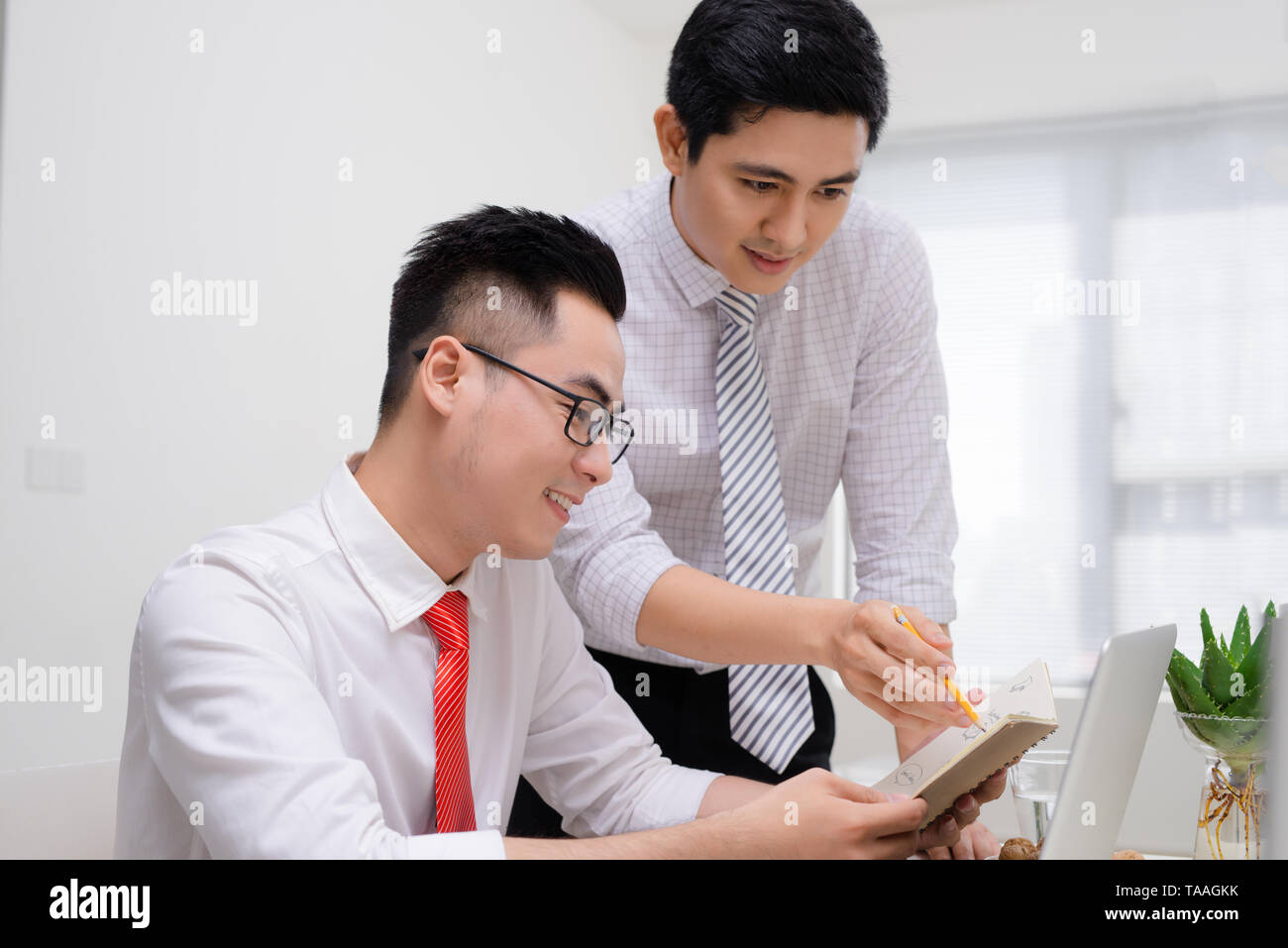 Two businessmen working together with computer at office desk, one of ...