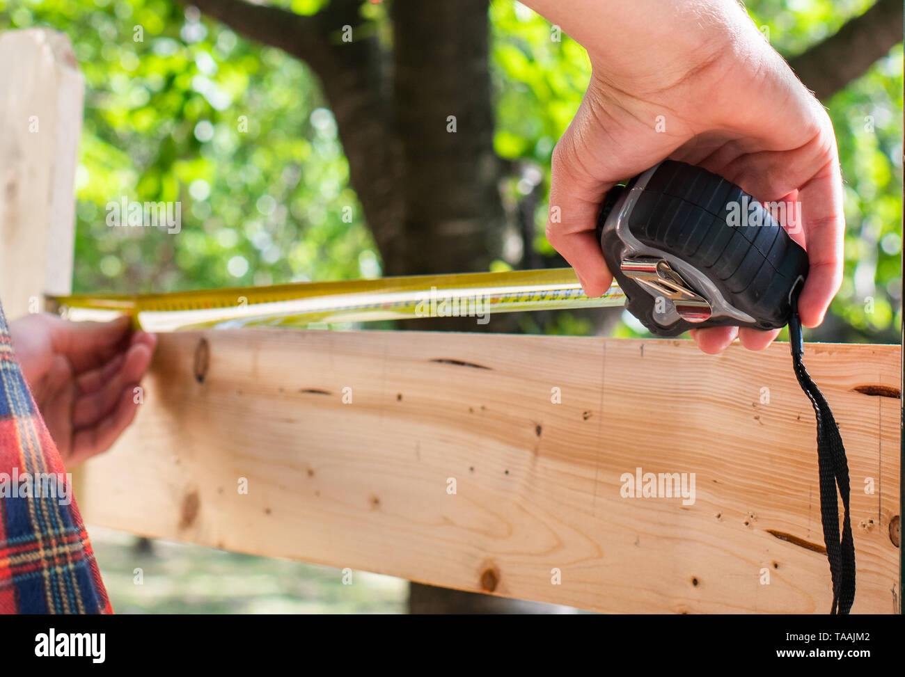 Man using yellow measuring tape to measure length Stock Photo - Alamy