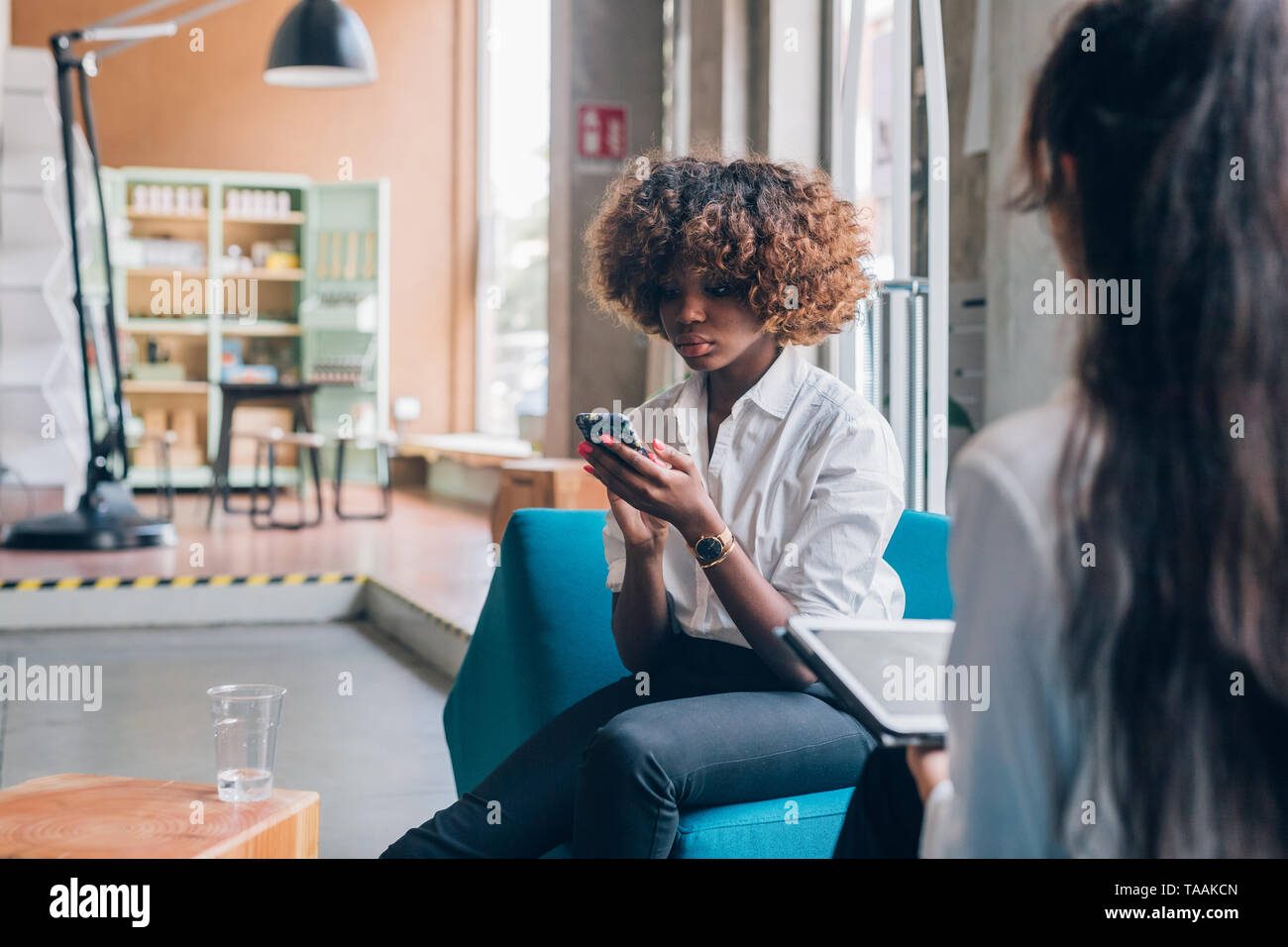 two young businesswomen working with smart device in modern office ...