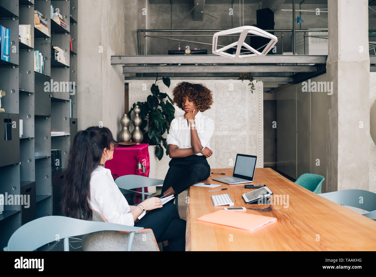 two multiracial young businesswomen having meeting in modern office ...