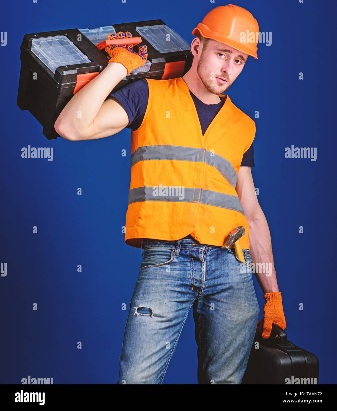 Man in helmet, hard hat holds toolbox and suitcase with tools, blue ...
