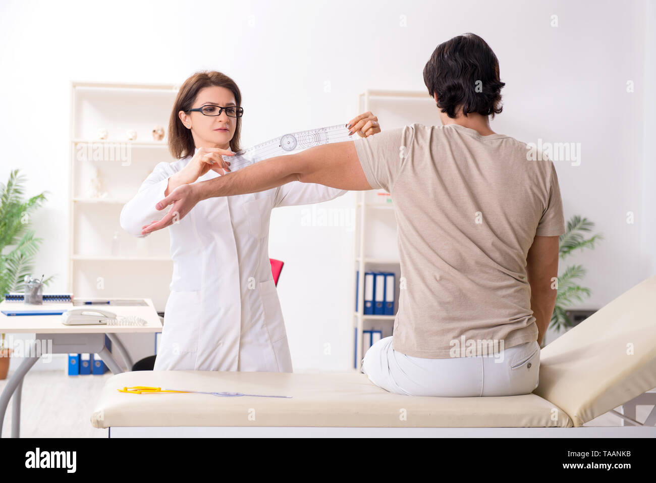 Female doctor checking patient's joint flexibility with goniometer ...