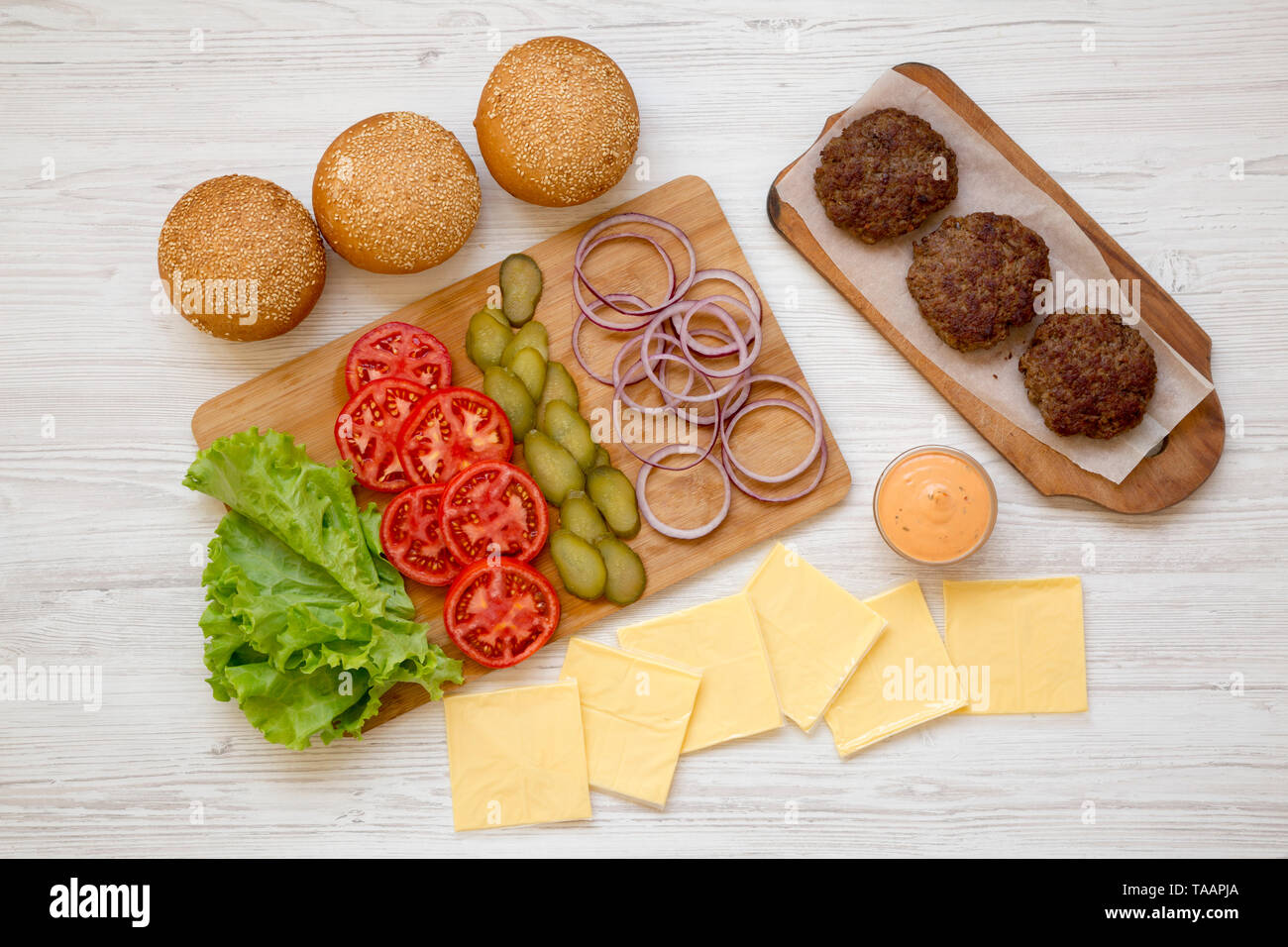 Cheeseburger ingredients on a white wooden surface, top view. Close-up ...