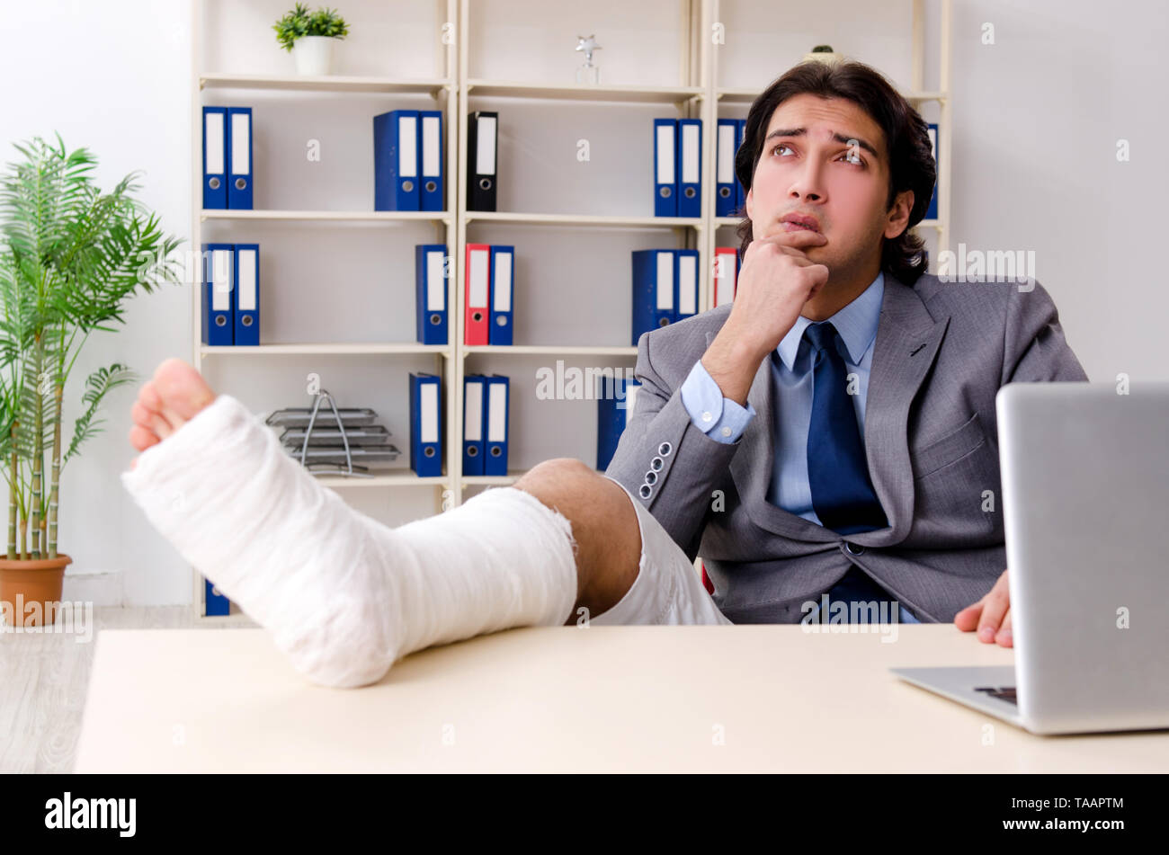 Leg injured employee working in the office Stock Photo - Alamy