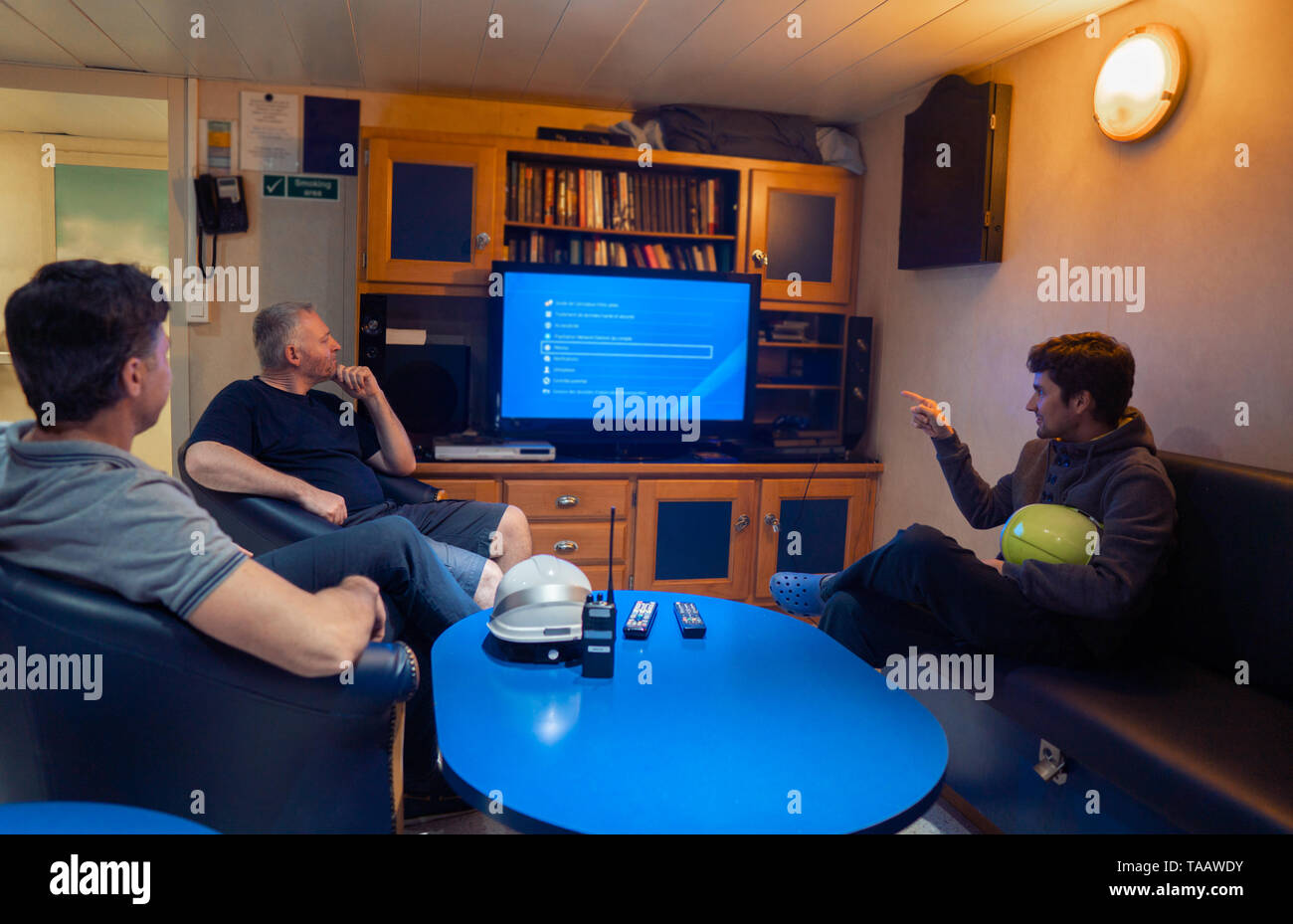 Happy team of ship officers watch TV onboard of vessel Stock Photo - Alamy