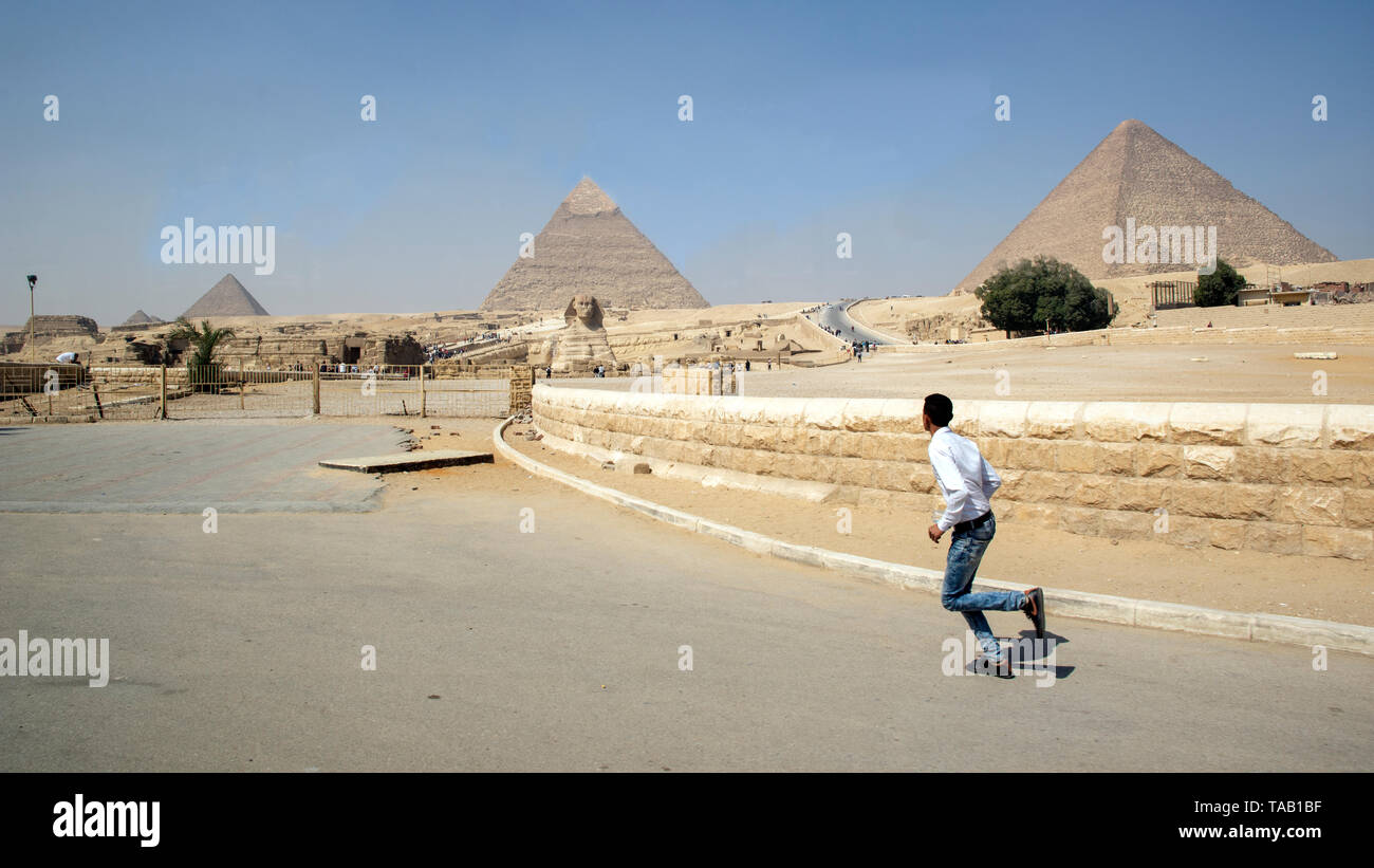 A man runs by a modern gate to the pyramid complex. The Great Pyramids ...