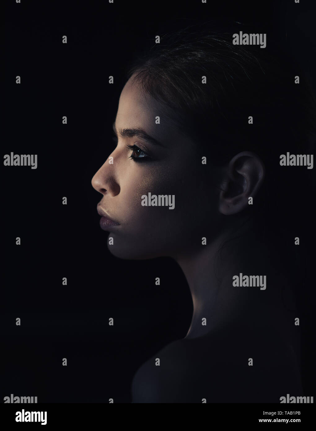 Face of pretty woman with make up in darkness. She is mystery for you ...