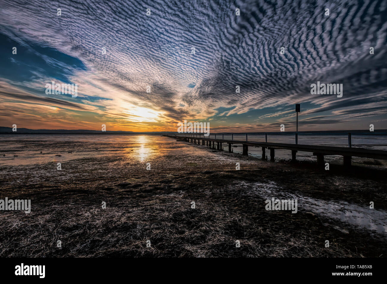 A long jetty on large tidal lake at sunset Stock Photo - Alamy