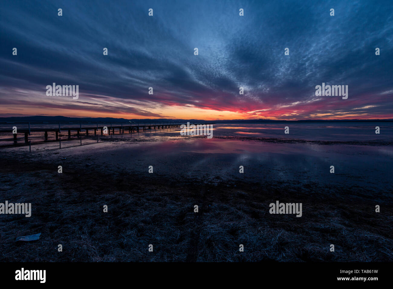 A long jetty on large tidal lake at sunset Stock Photo - Alamy