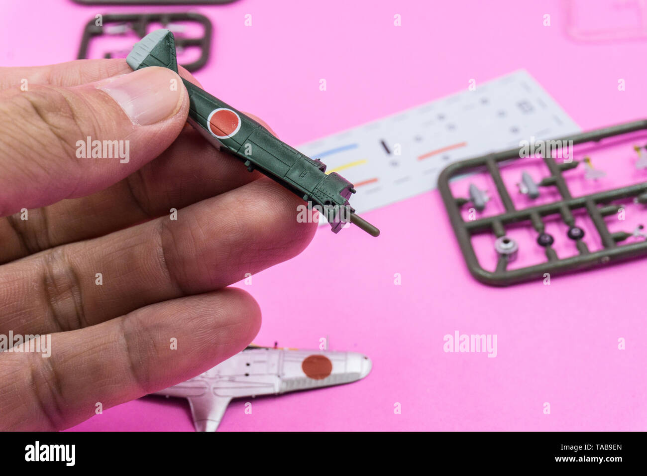 Male hand assembly fighter plane scale model in pink background Stock ...