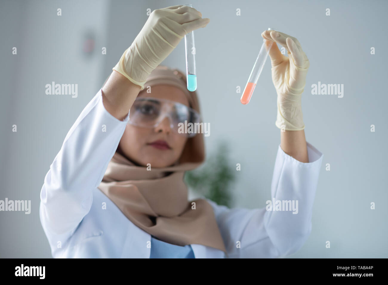 Raising test tubes. Female chemist wearing white coat raising test ...