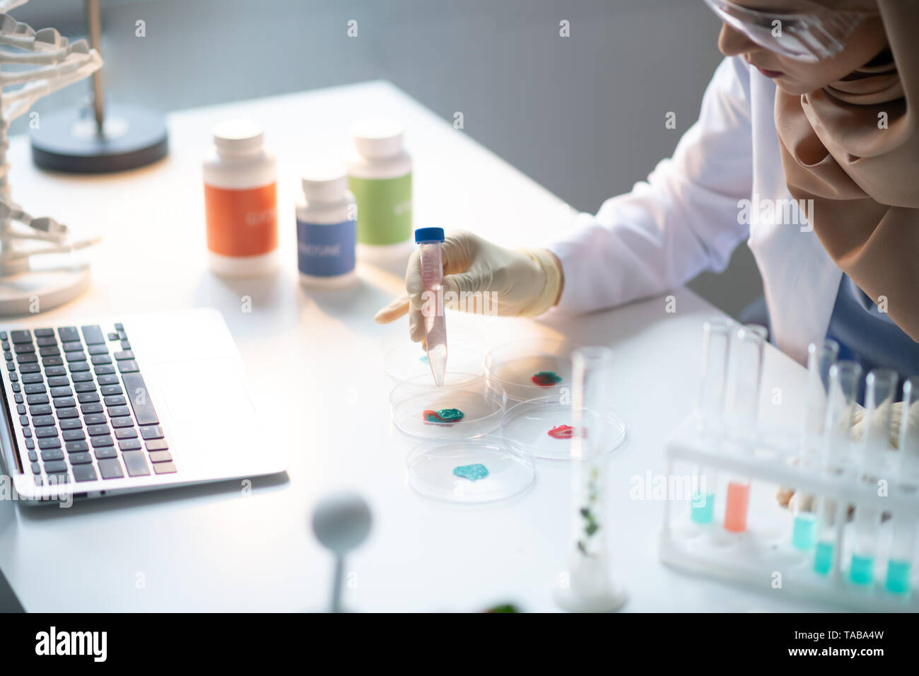 New chemicals. Professional chemist wearing glasses sitting near laptop ...