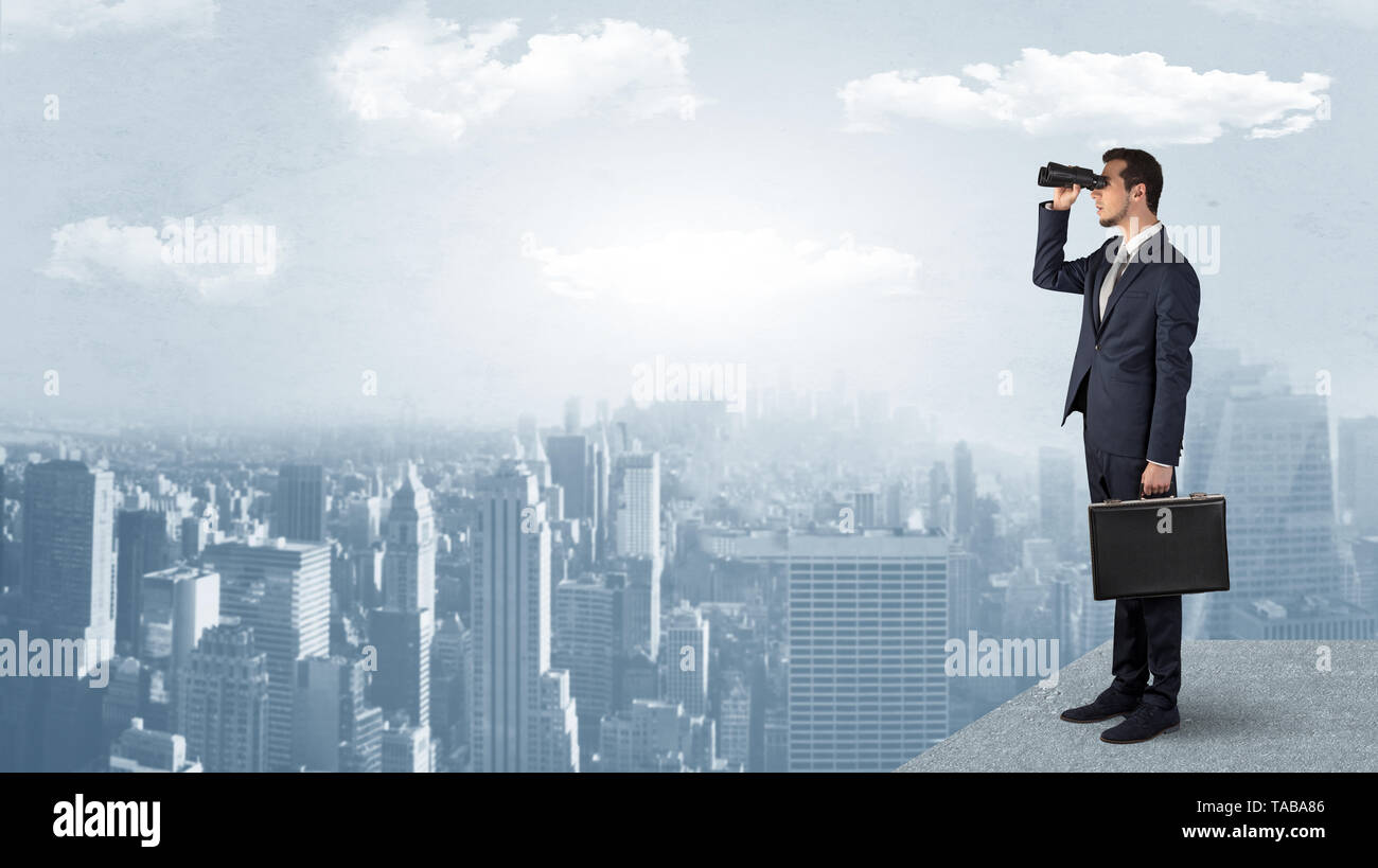 Businessman looking forward to a city with binoculars from skyscraper ...
