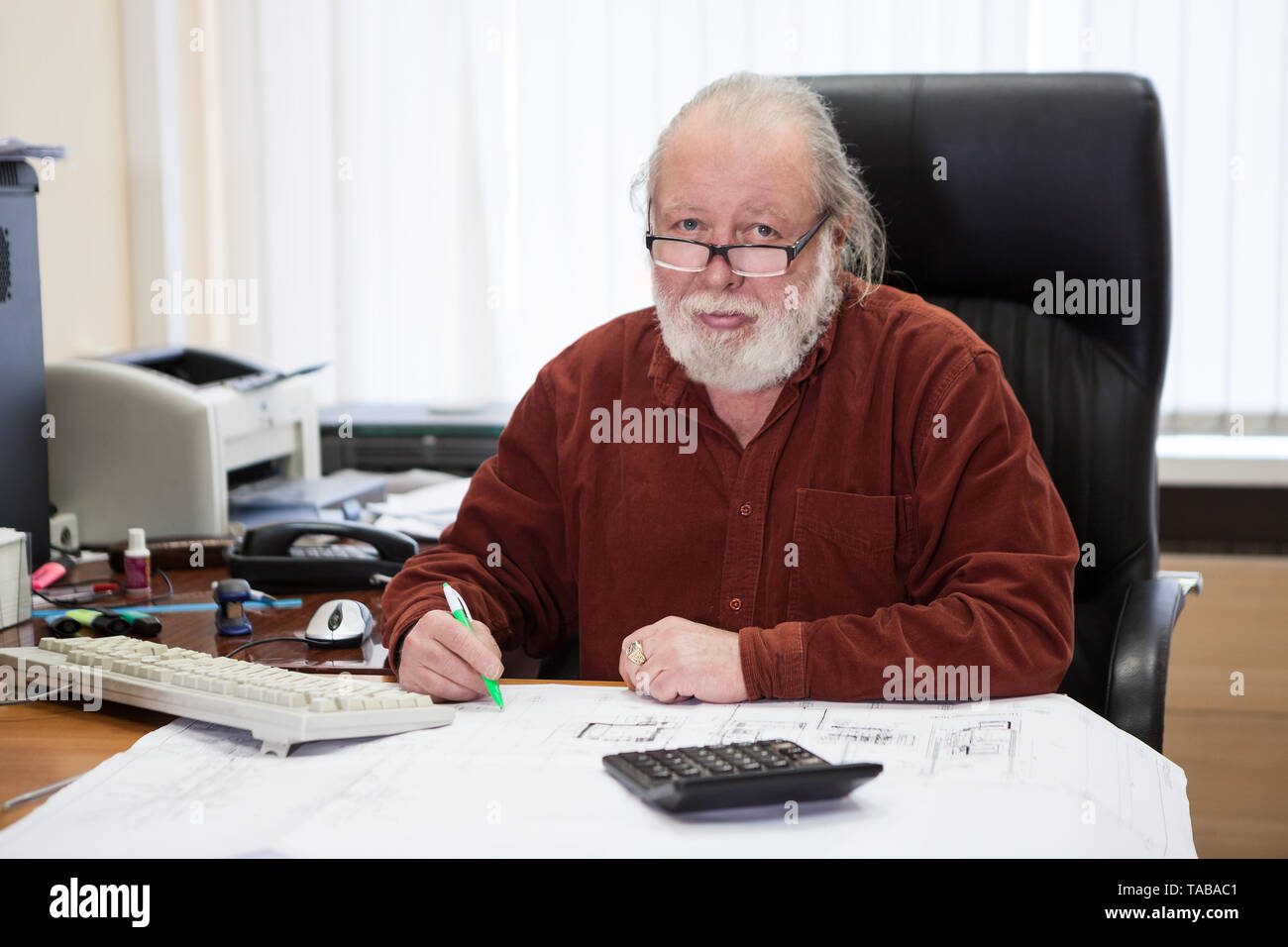 Architectural senior engineer working with blueprints and documents ...