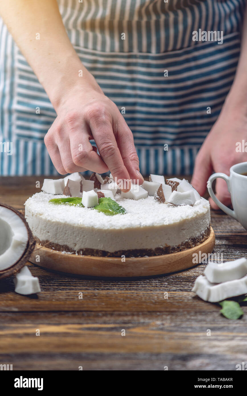 Confectioner decorates coconut raw cake with white pulp and mint on ...