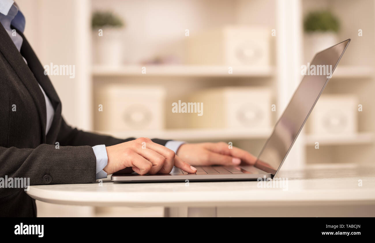 Business woman below chest working on her laptop in a cozy environment ...