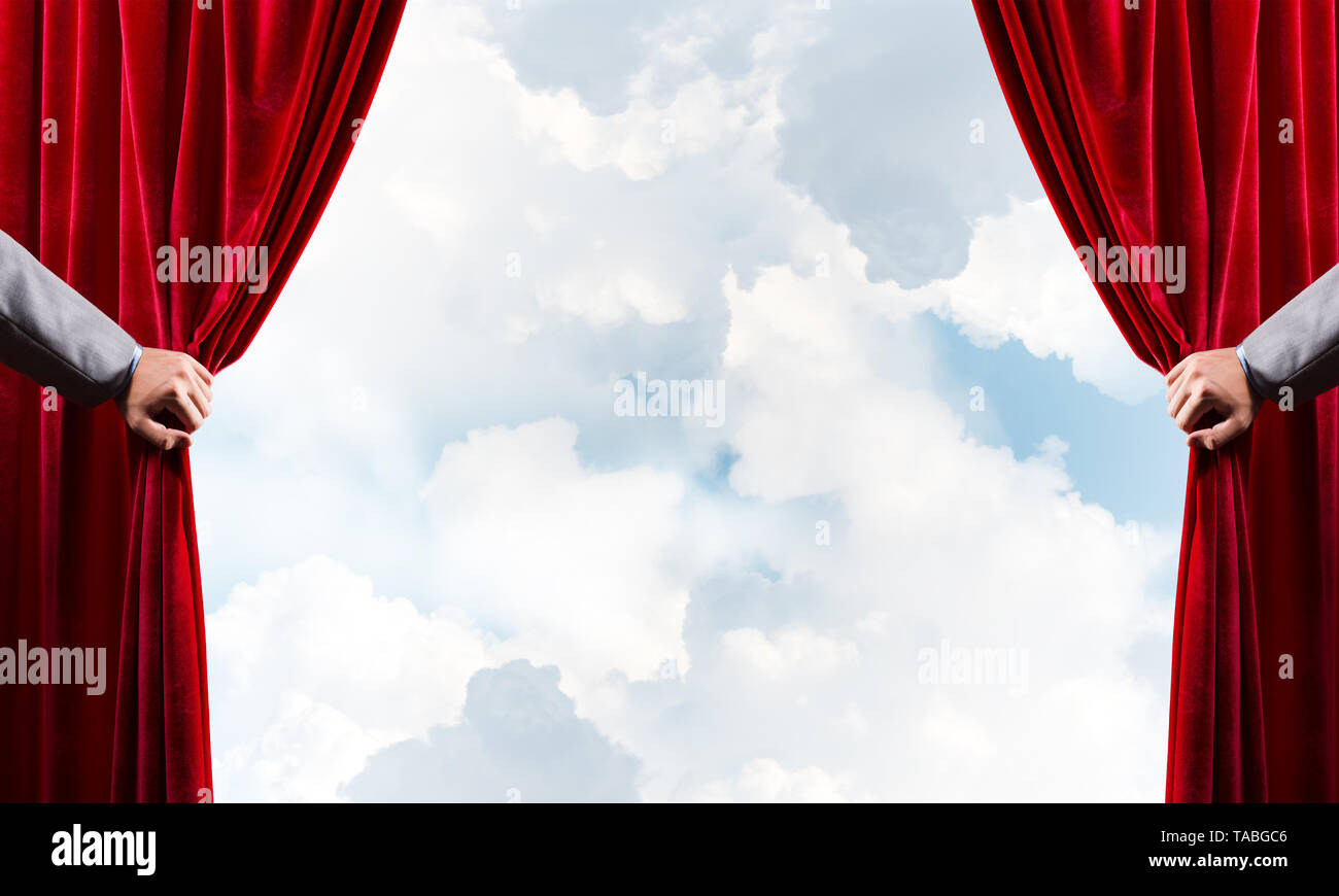 Cloudy landscape behind red curtain and hand holding it Stock Photo - Alamy