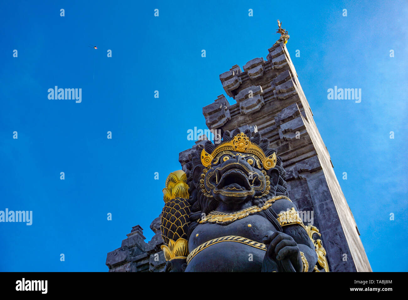 A temple gate in Bali with a Barong head statue. Barong is a lion-like ...