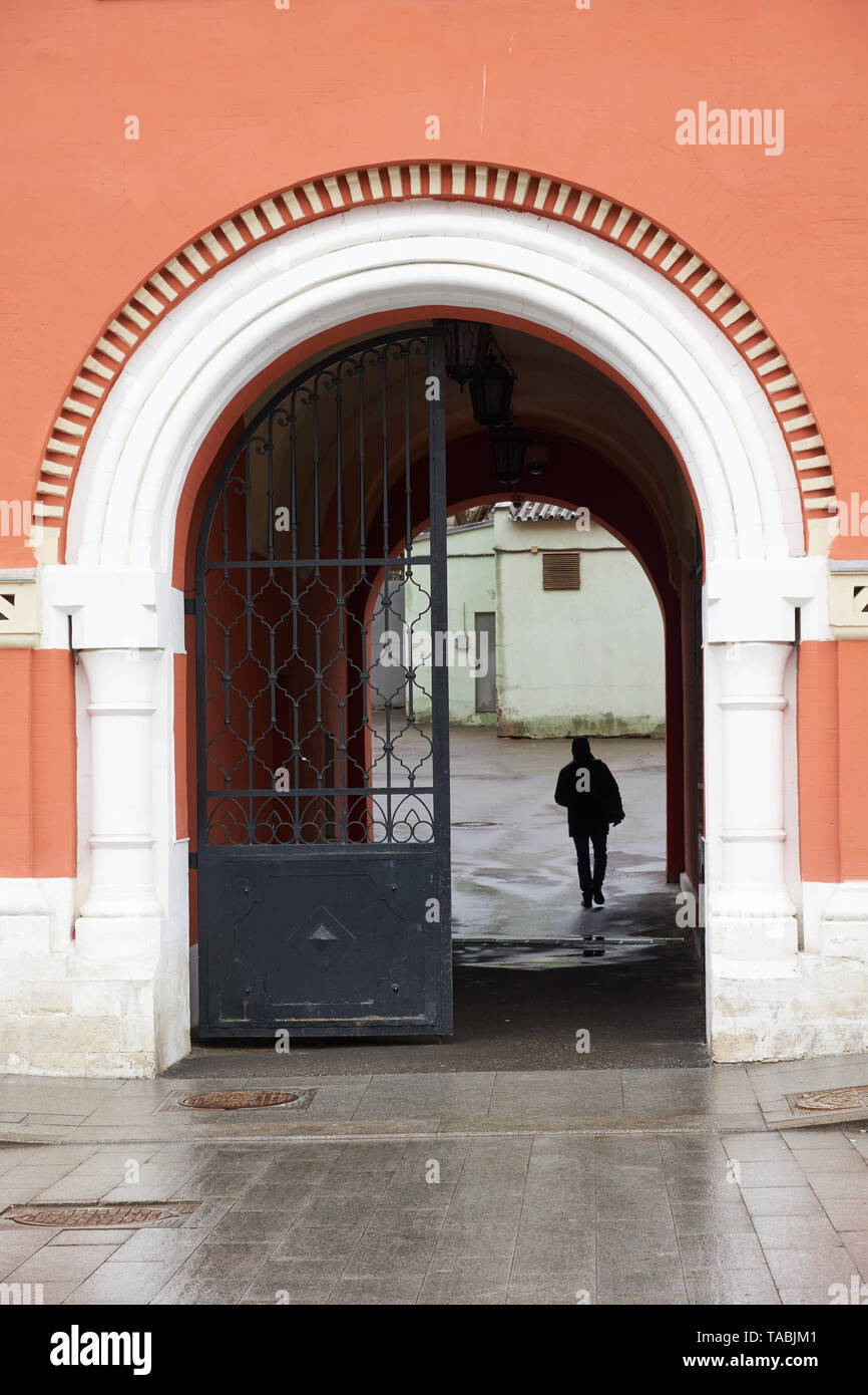 Arch in red house on Manezhnaya street in Moscow. Man walks in the yard ...