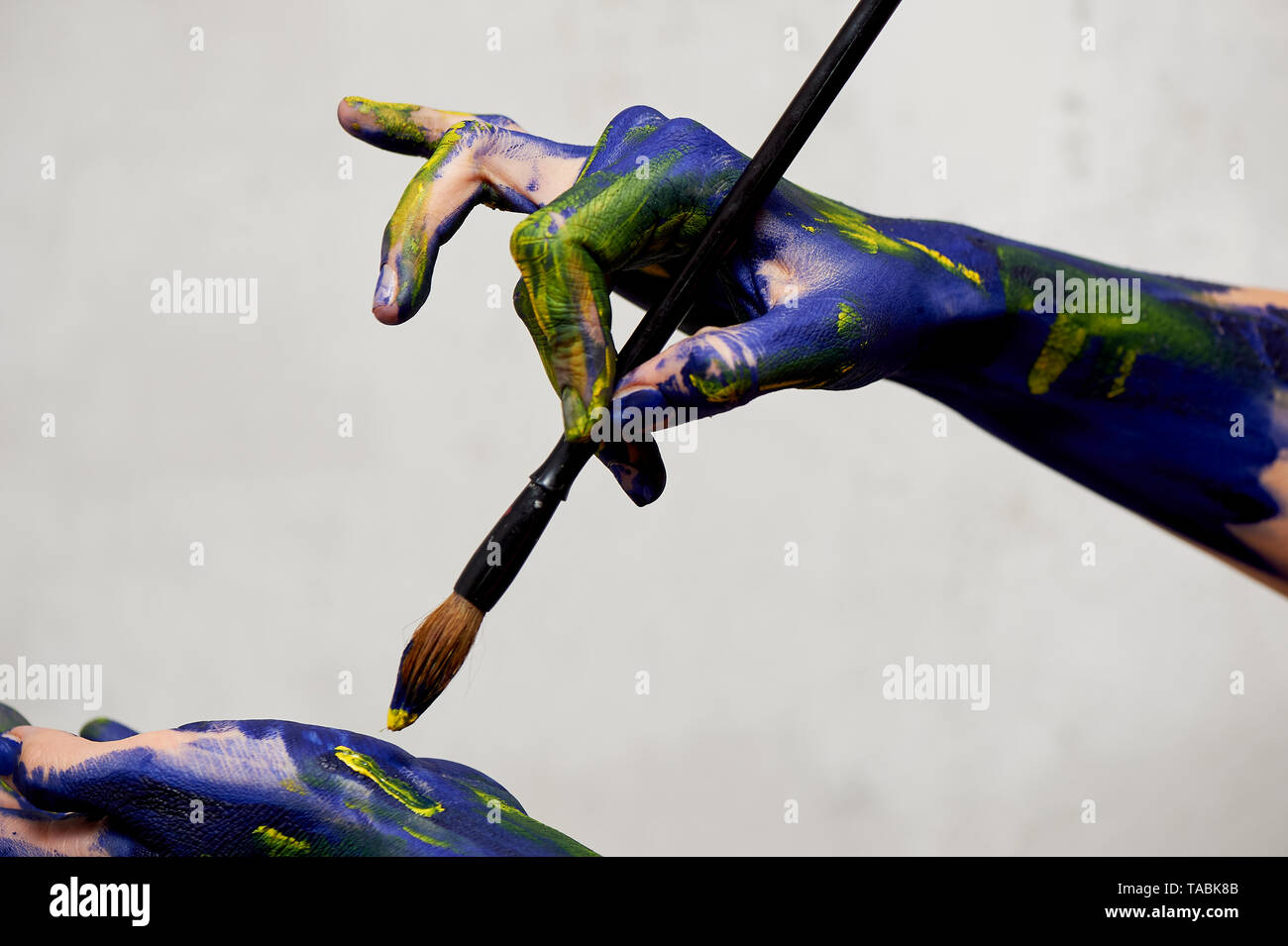 Graceful hands of the artist with a brush. Hands in blue and yellow ...