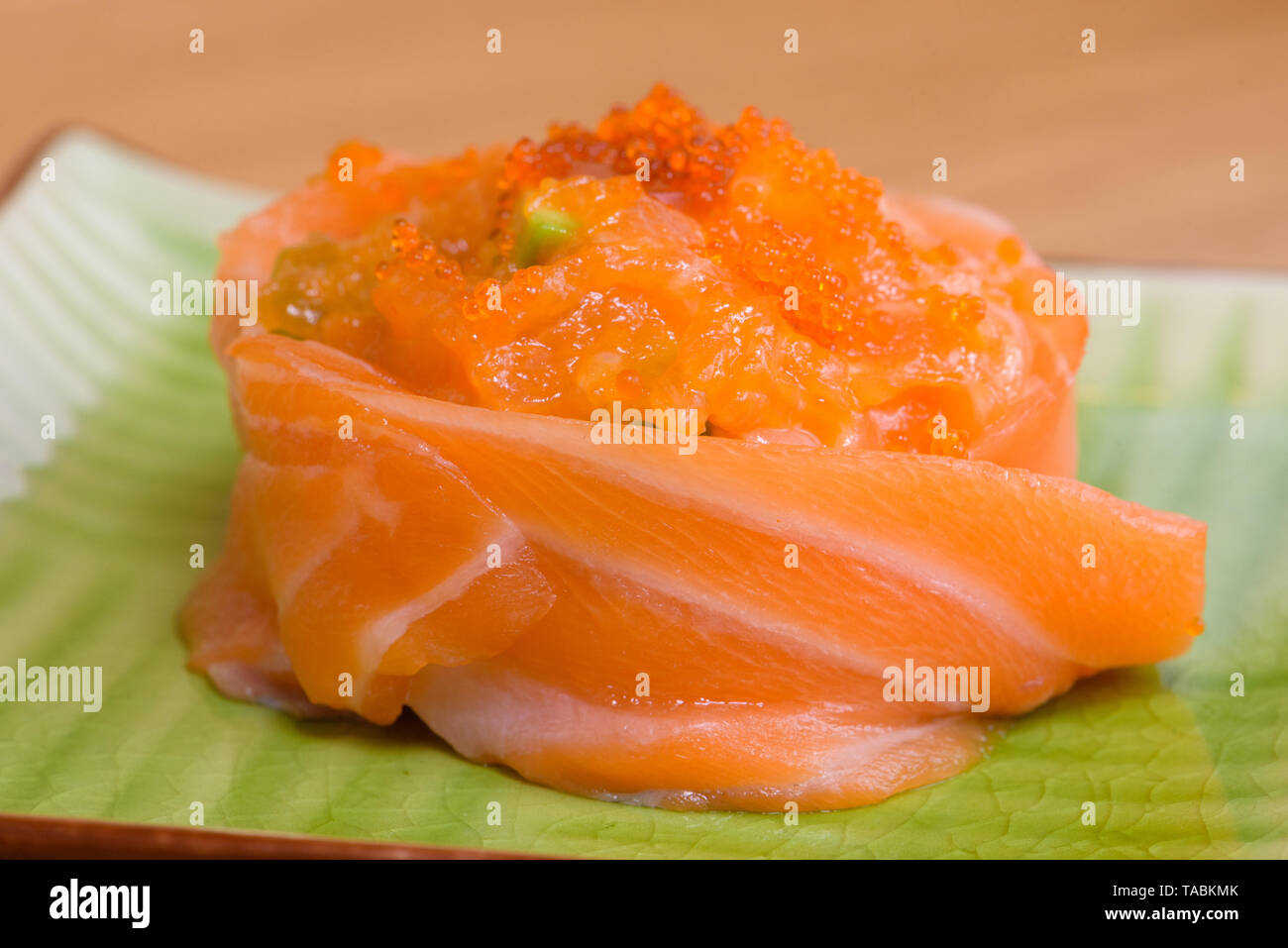 salmon sashimi with caviar and avocado served on a plate, seen from 45 ...