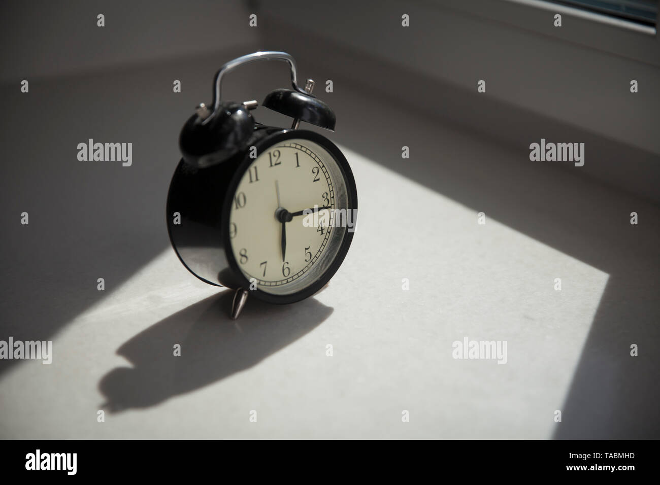 The alarm clock is on the window. It shows time at a quarter to six ...