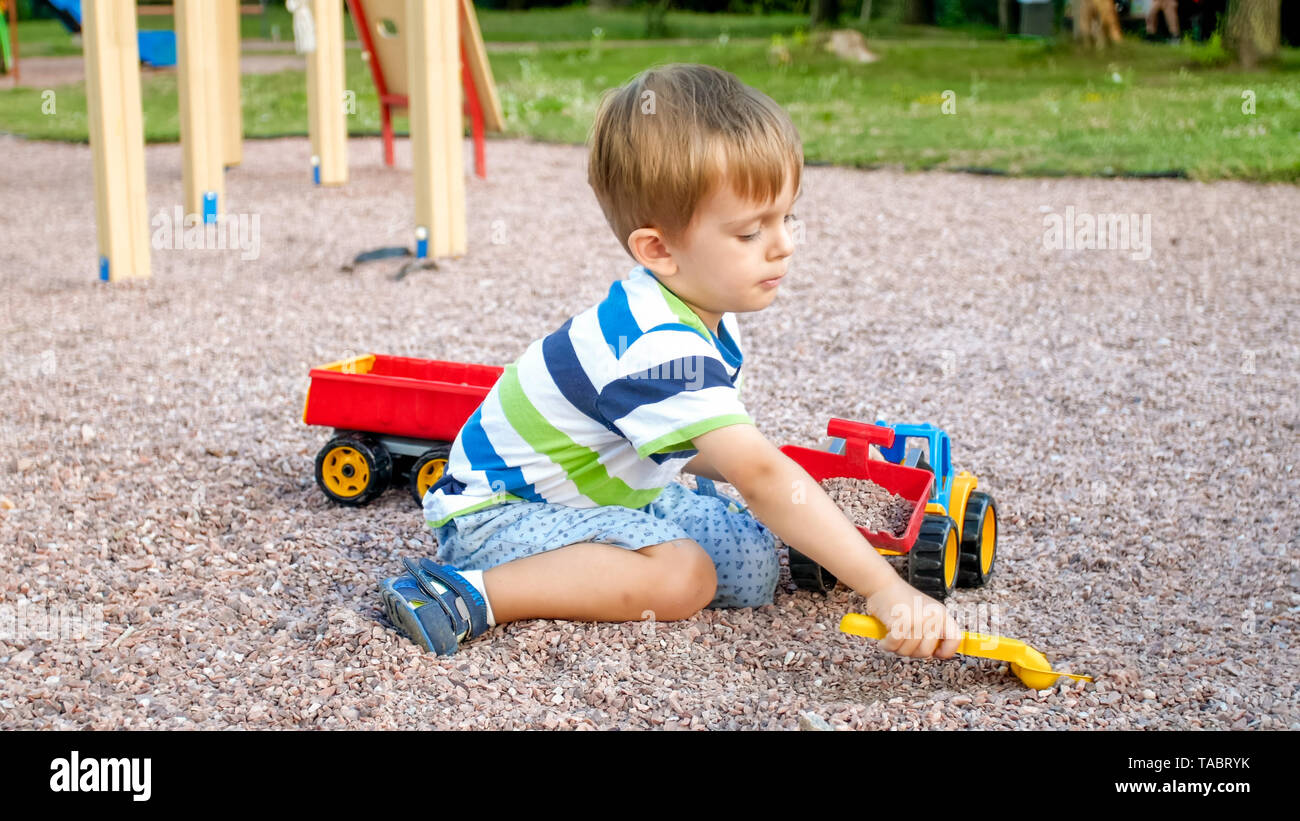 Portrait of cute 3 years old toddler boy sitting on the playground at ...