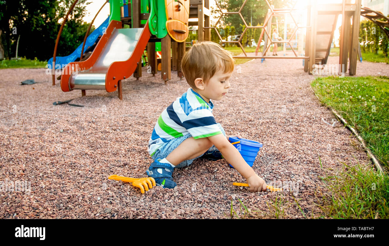Portrait of little 3 years old toddler boy sitting on the playground ...