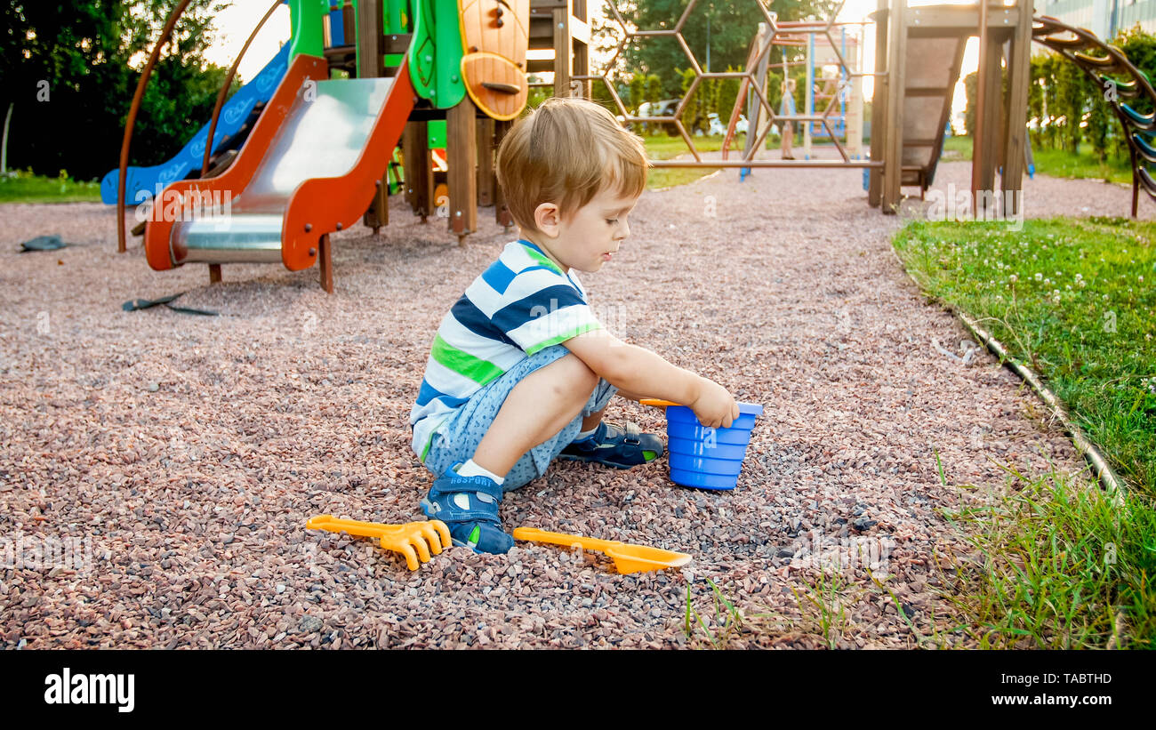 Photo of adorable 3 years old little boy sitting on the playground and ...