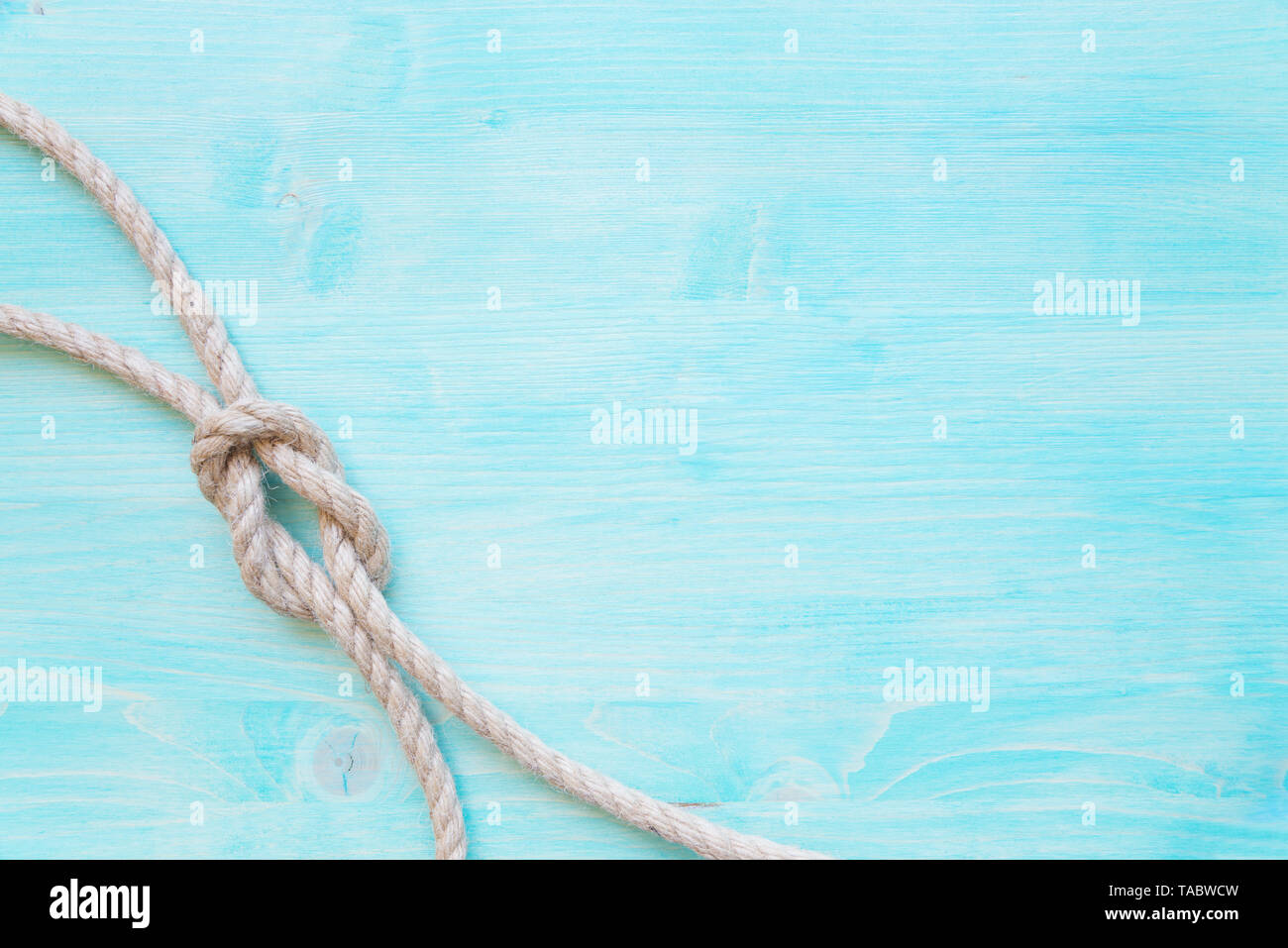 Rough hemp rope tied knot sea is on the background of blue faded wooden ...