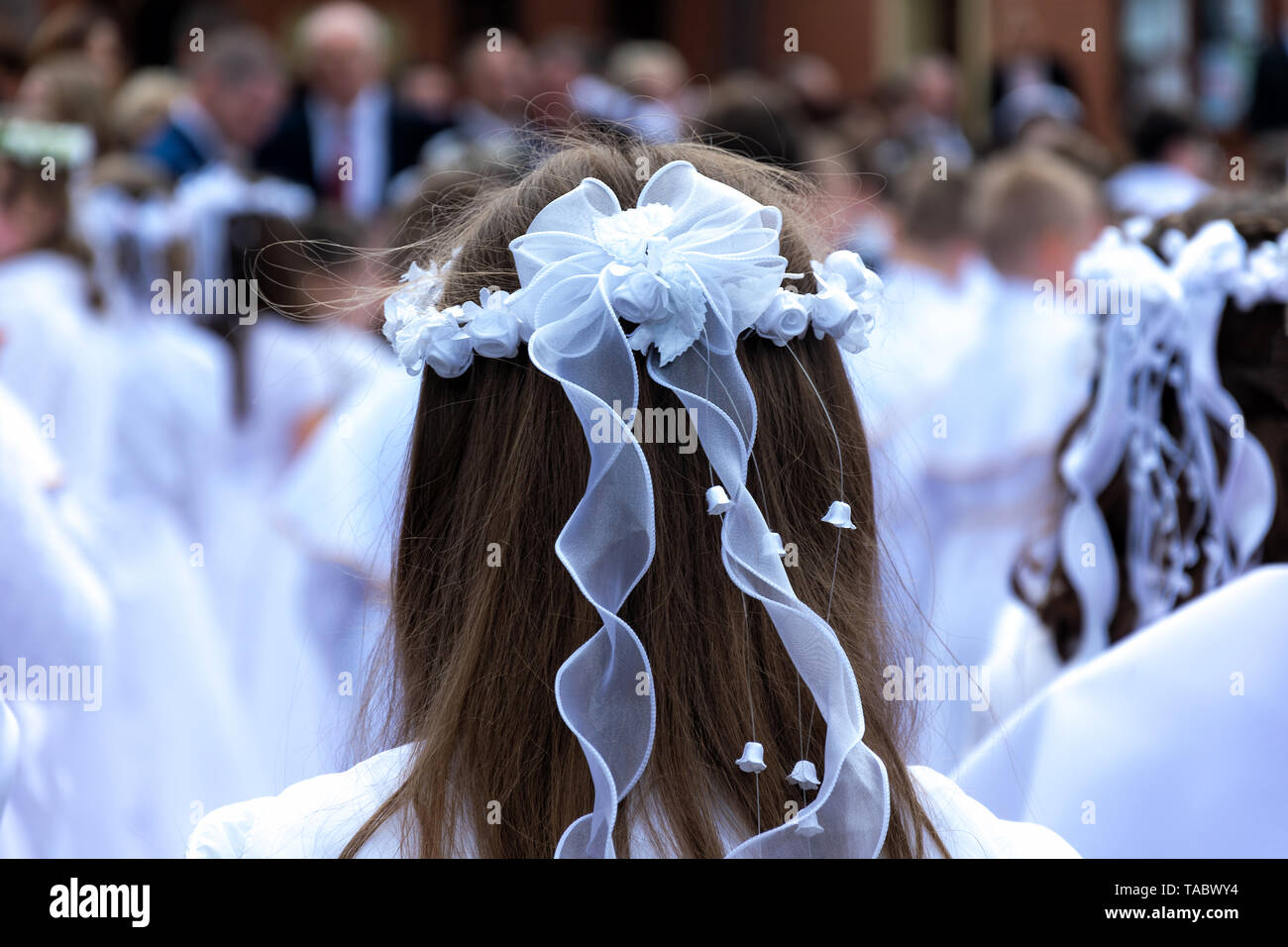 A group of children in solemn white clothes is waiting in front of the ...