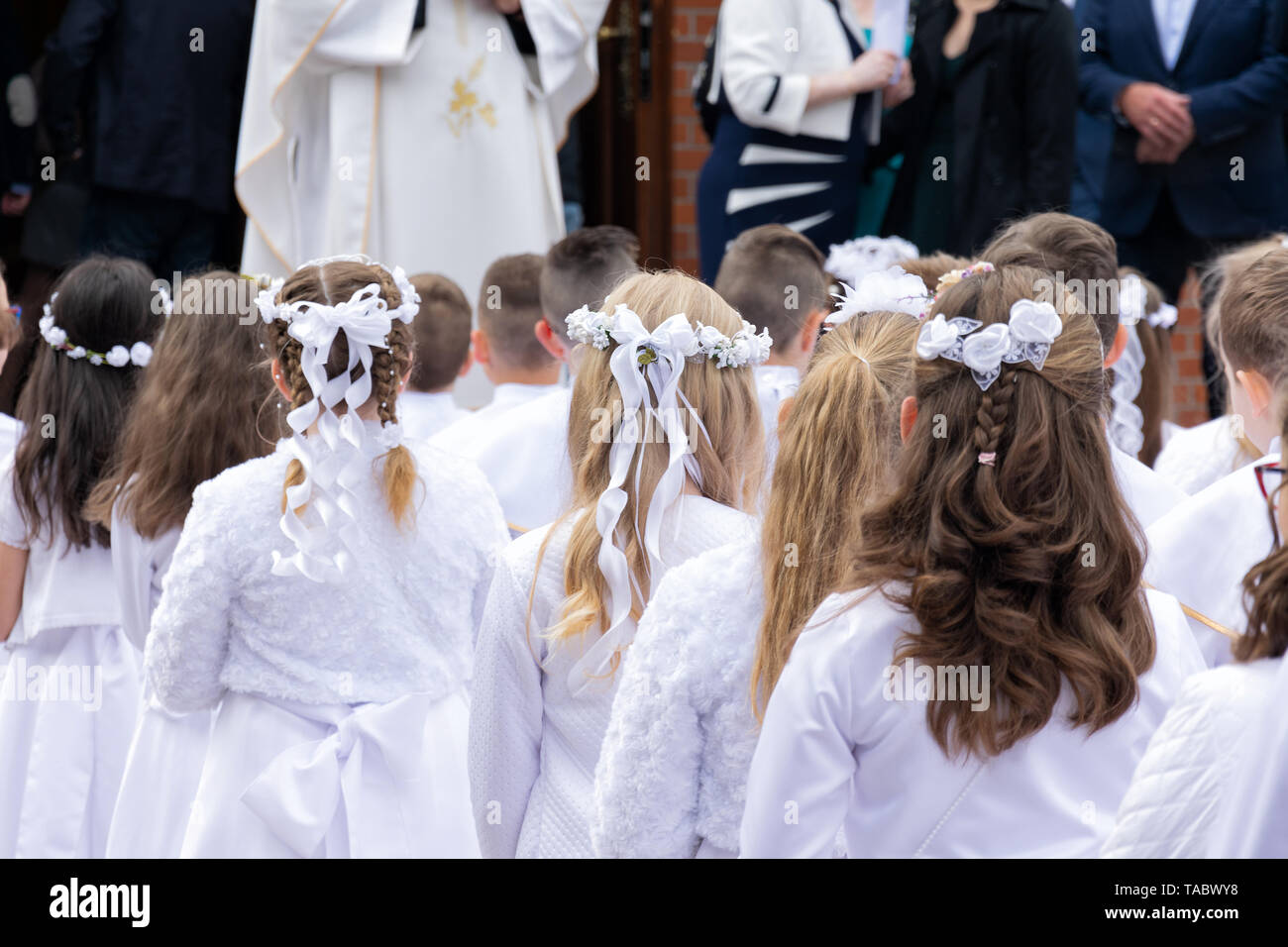 A group of children in solemn white clothes is waiting in front of the ...