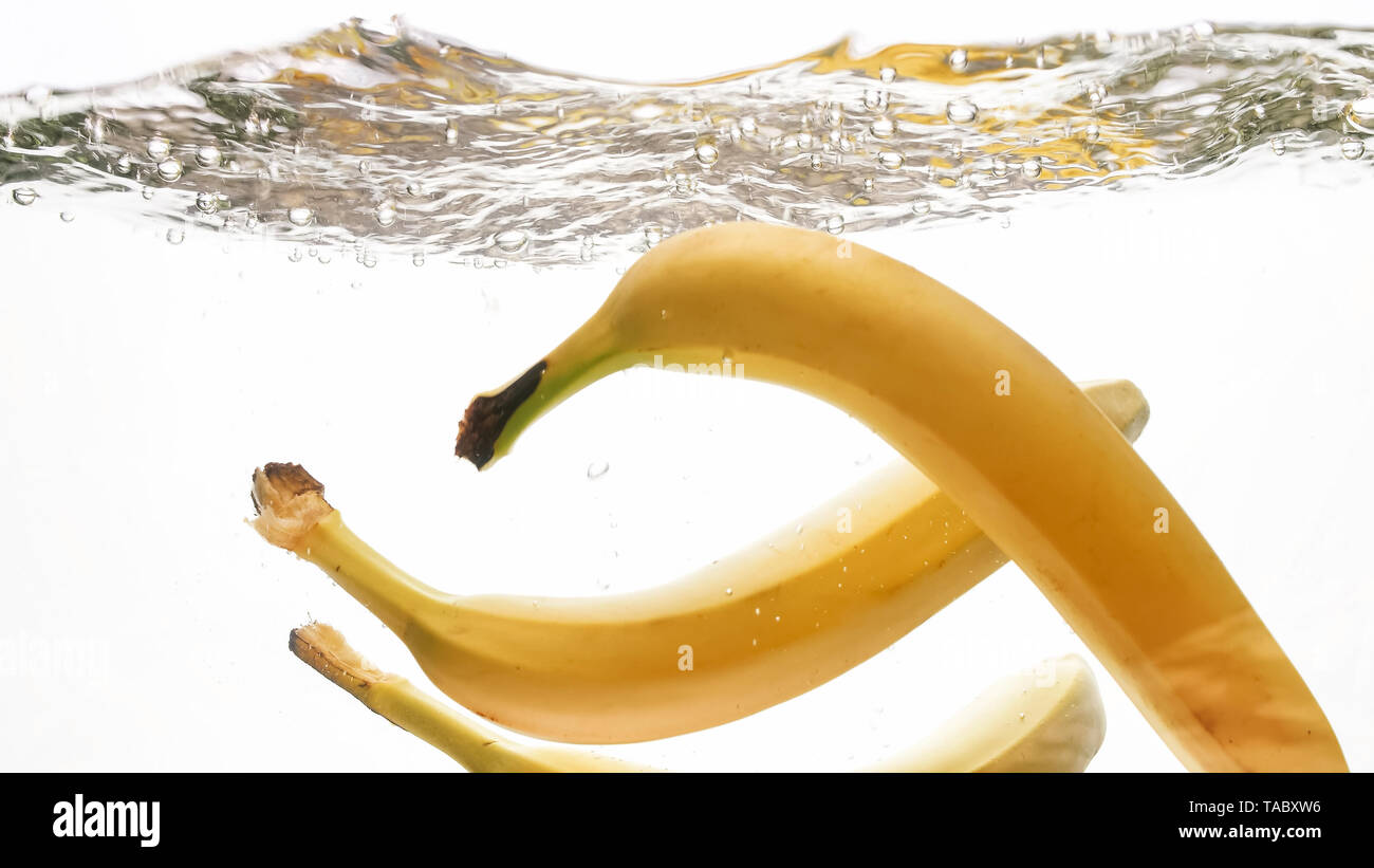 Closeup beautiful image of bananas falling in clear water against white ...