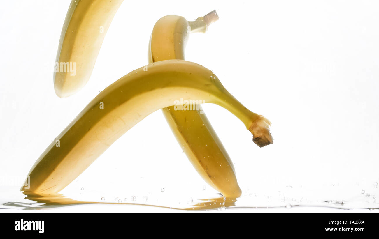Closeup beautiful image of bananas falling in clear water against white ...